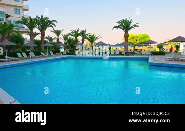 Beautiful view of resort swimming pool with palm trees near Aegean Sea ...
