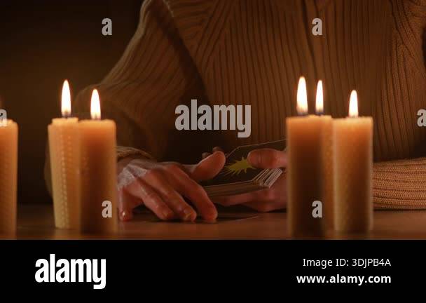 Mystic male seer performing tarot card reading by flickering ...