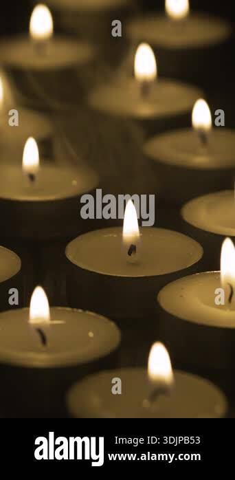 Group of burning small candles at a memorial. Many glowing tea lights ...