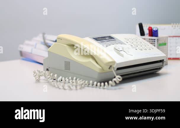 A man hands using a fax machine, placing paper into the tray and ...
