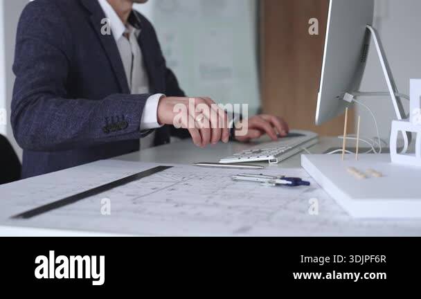 Professional architect typing at keyboard in modern office, surrounded ...