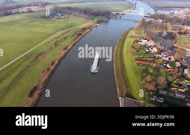 Aerial view of river with cargo ship, arched bridge, and mixed use ...