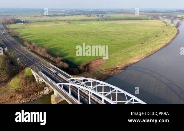 Aerial view of arched highway bridge over curving river, linking green ...