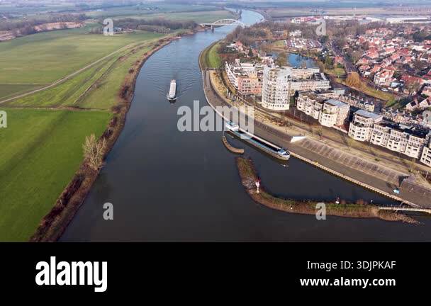 Aerial view of riverside cityscape with curving river, cargo ship ...