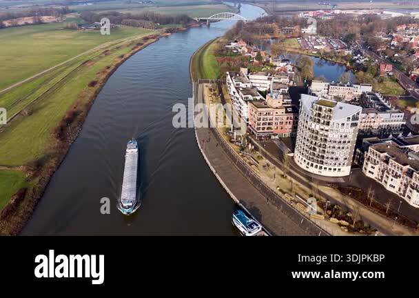 Aerial view of river bend with cargo vessel, docked boats, bridge, and ...