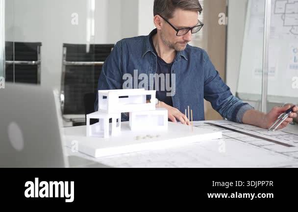 Stressed male architect gripping his head while analyzing blueprints ...
