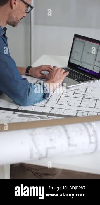 Professional architect drawing detailed blueprints on a desk covered ...