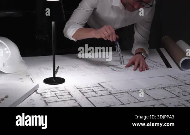 Architect carefully planning building blueprints at a desk, designing ...