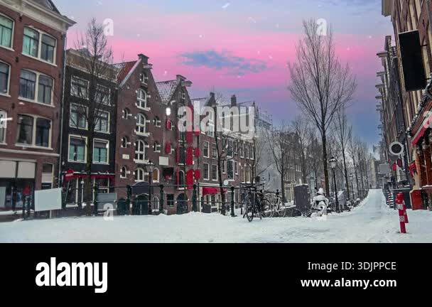 Winter street scene with falling snow in city streets at sunset ...