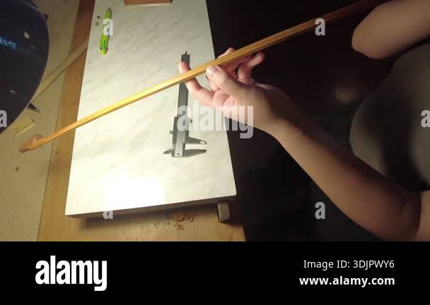 A person's hands hold a wooden stick, measuring it with a caliper tool ...