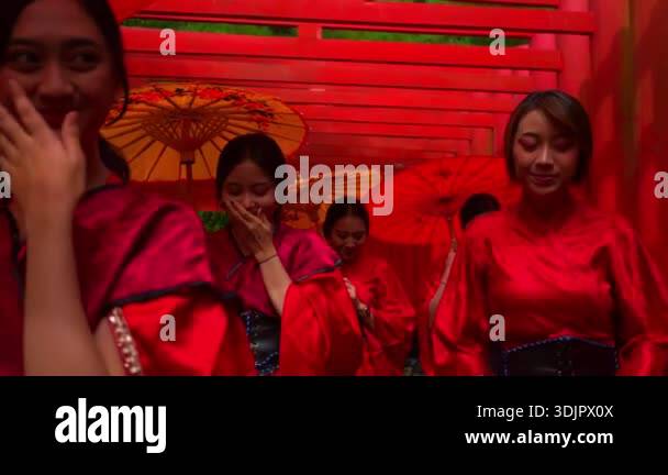 A group of beautiful young Asian women in red traditional dresses ...