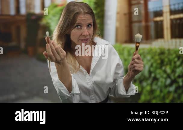Woman holding makeup and paint brushes, showing brushes with raised ...