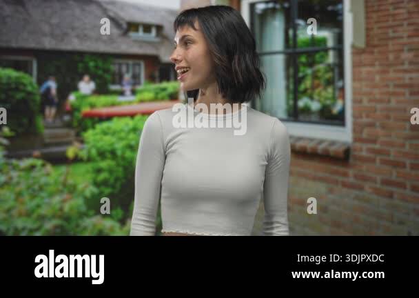Woman points thumb over shoulder at suburban brick building entrance ...