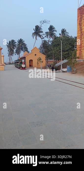 Vintage green train on tracks near yellow building in tropical setting ...