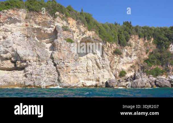 Sharp tall rocky cliffs and coniferous trees visible above clear green ...
