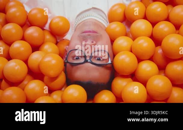 A creative flat lay shot of a man's face framed by vivid orange balls ...