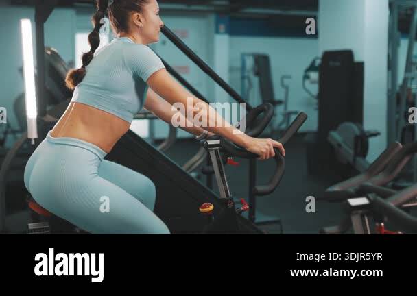 Fit woman in sportswear exercising on a stationary bike during a cardio ...