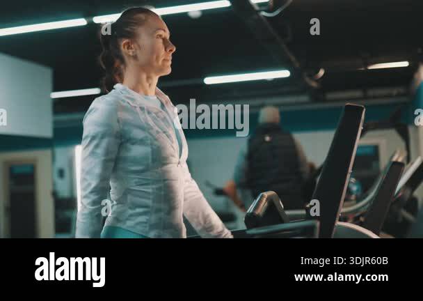 Athletic woman walking on a treadmill doing her cardio workout routine ...