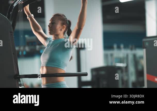 Muscular woman doing lat pulldown exercise in a fitness gym for back ...