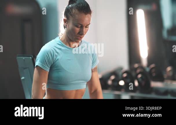 Determined woman performing a dumbbell lateral raise exercise for ...