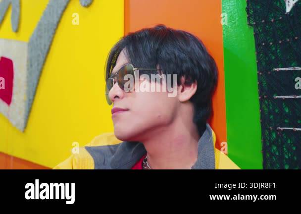 Headshot of a trendy young man in sunglasses and a yellow jacket ...