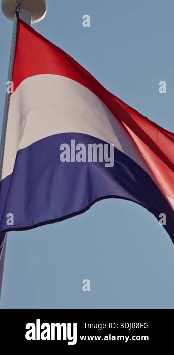 Netherlands flag waving on flagpole against blue sky, telephoto Stock ...
