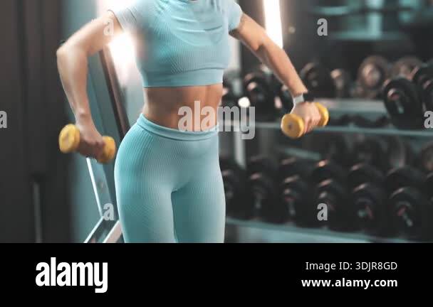 Strong woman performing lateral raises with dumbbells during a shoulder ...