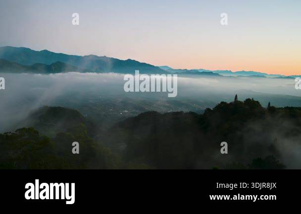 A breathtaking view of a thick sea of clouds rolling over the mountains ...