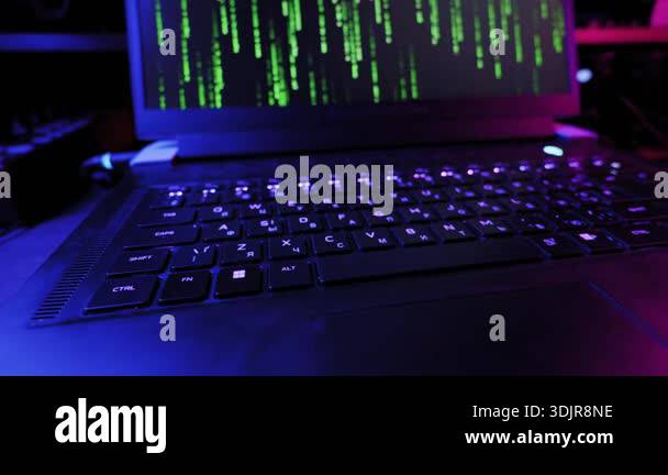 Laptop keyboard is illuminated by blue light with a screen displaying ...