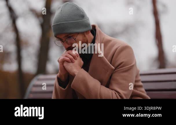 Experiencing emotional distress, a lonely man sits on a park bench ...