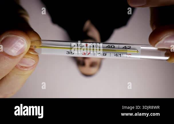 Male hands hold a glass mercury thermometer showing a dangerously high ...