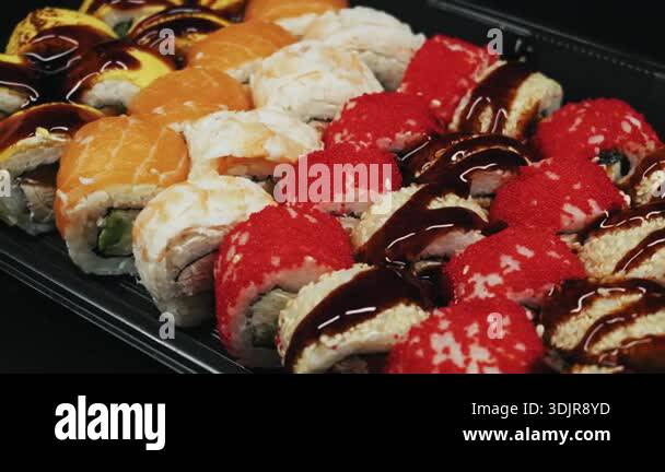 Variety of sushi rolls with salmon eel and red roe sit arranged in a ...