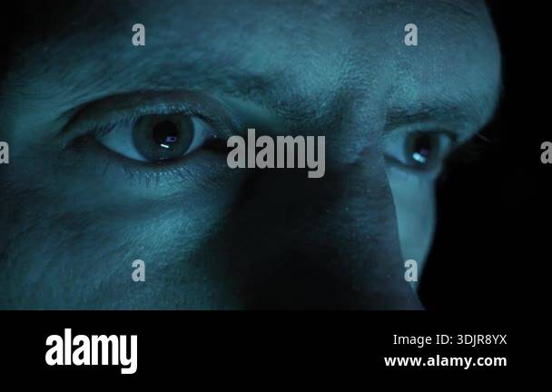 Male eyes stare intensely at a computer screen with digital reflections ...