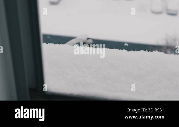 A close-up view of fresh snow piled high on a window ledge, with a ...