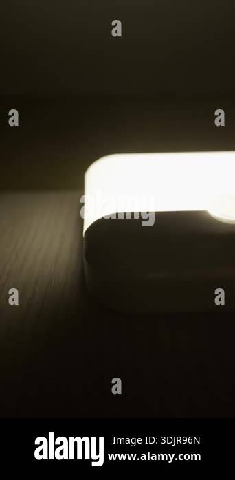 A close-up panning shot captures a modern LED night light glowing on a ...