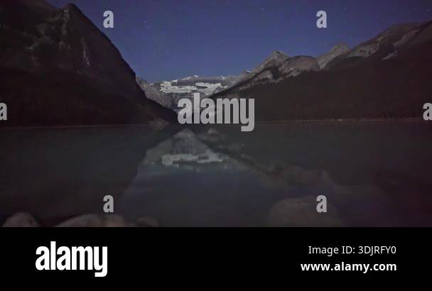 Mountains reflecting in calm lake at night. Lake Louise, Banff National ...