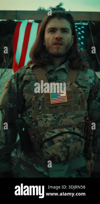 American soldier salutes in front of waving flag at night on a military ...