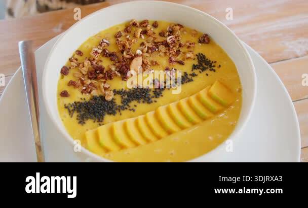 Mango tropical fruit smoothie bowl topped with sliced fruit and cereal ...