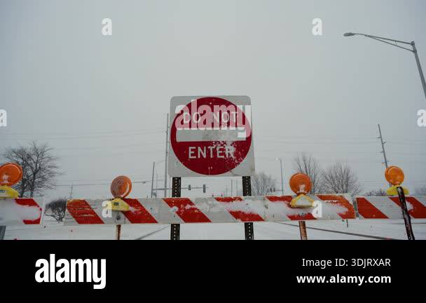 A red Do Not Enter sign stands behind road closure barriers during ...