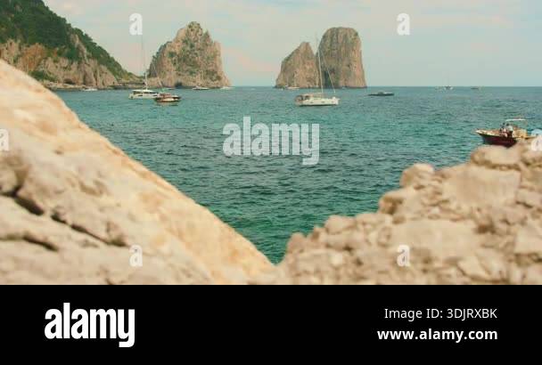 Sailboats and motorboats drift near iconic Faraglioni limestone sea ...