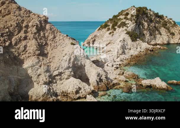 Steep rocky cliffs forming narrow turquoise cove on sunny coast in ...