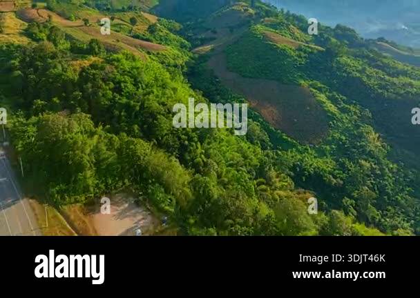 Aerial view of A winding road twisting across tall mountain peaks in ...
