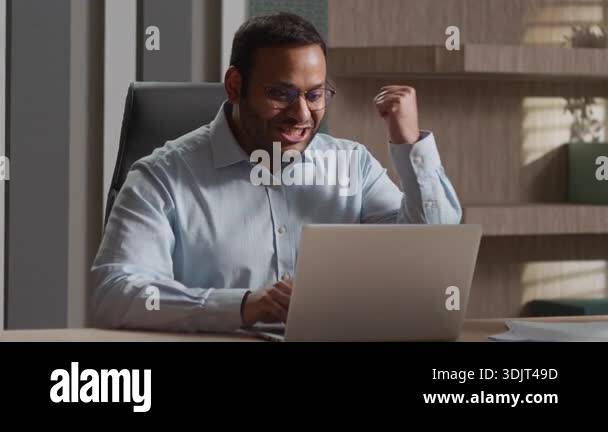 Happy cheerful Indian business man celebrating victory at office laptop ...