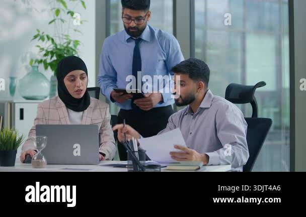 Business Arabian team three Indian Muslim colleagues in office discuss ...