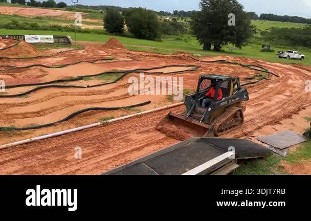 Orlando, Florida, USA - 07.17.2024: A skid steer spreads red clay and ...