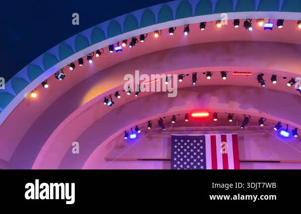 Colorful stage lights line the curved roof of an outdoor amphitheater ...