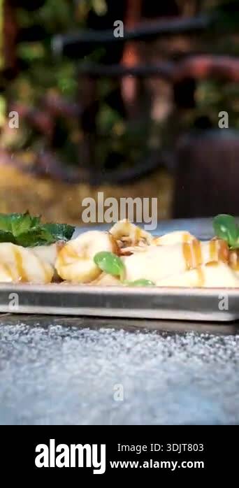 Thin pancakes with banana sprinkled with powdered sugar in the fall on ...