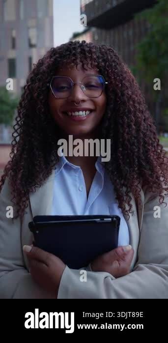 Vertical. African professional smiles at the camera in a modern urban ...