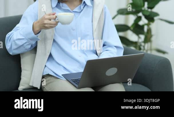 Coffee break. Woman with aromatic drink and laptop on sofa indoors ...