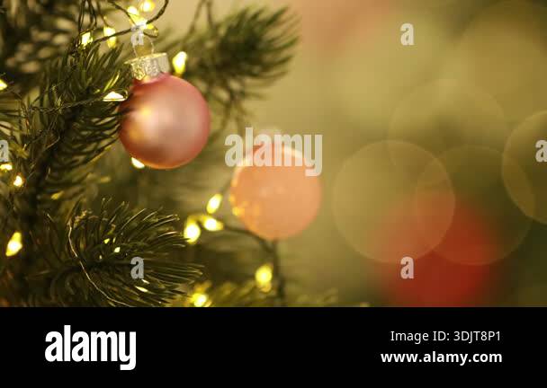 Christmas bauble hanging on fir tree branch against blurred lights ...